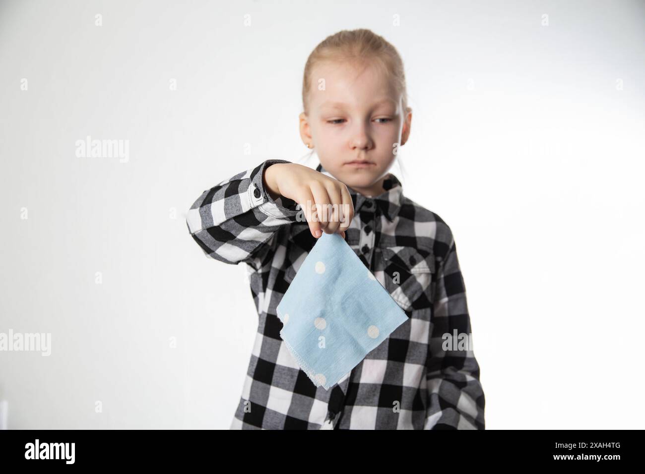a sad girl aged seven years old holds a handkerchief in her hand ...