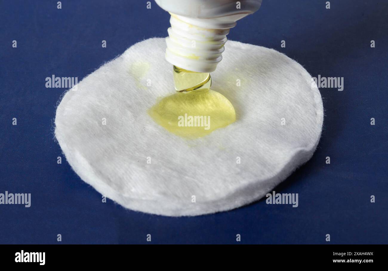 The yellow ointment is squeezed out of the tube onto a white cotton pad ...