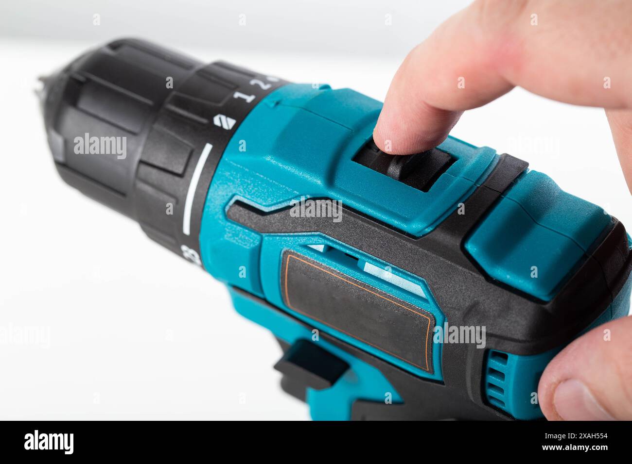 A worker's finger switches the rotation direction switch on a drill ...