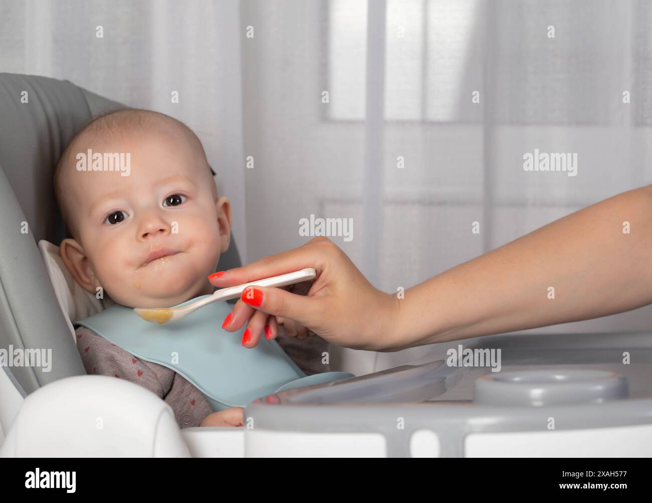 The first feeding with fruit puree for a baby boy who is 6 months old ...