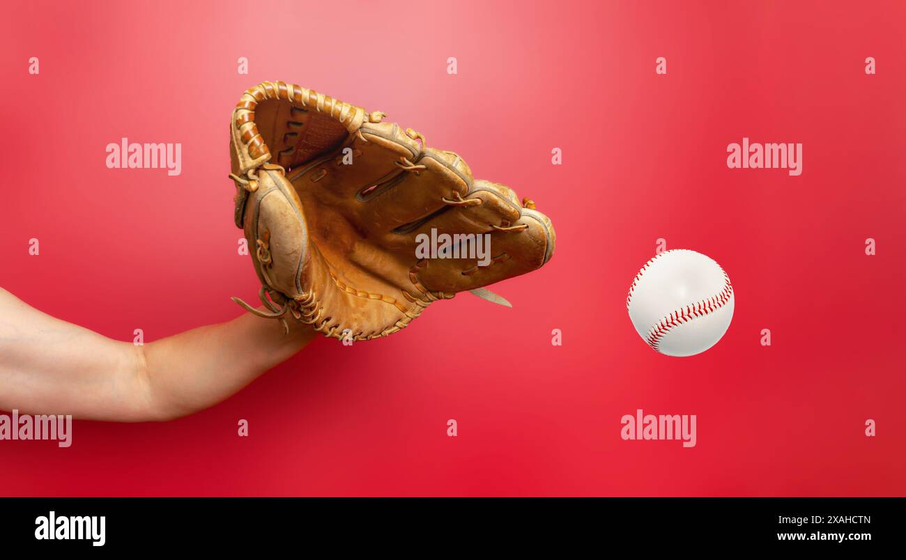 Female baseball gloved hand catches ball. Red background. Active sport ...