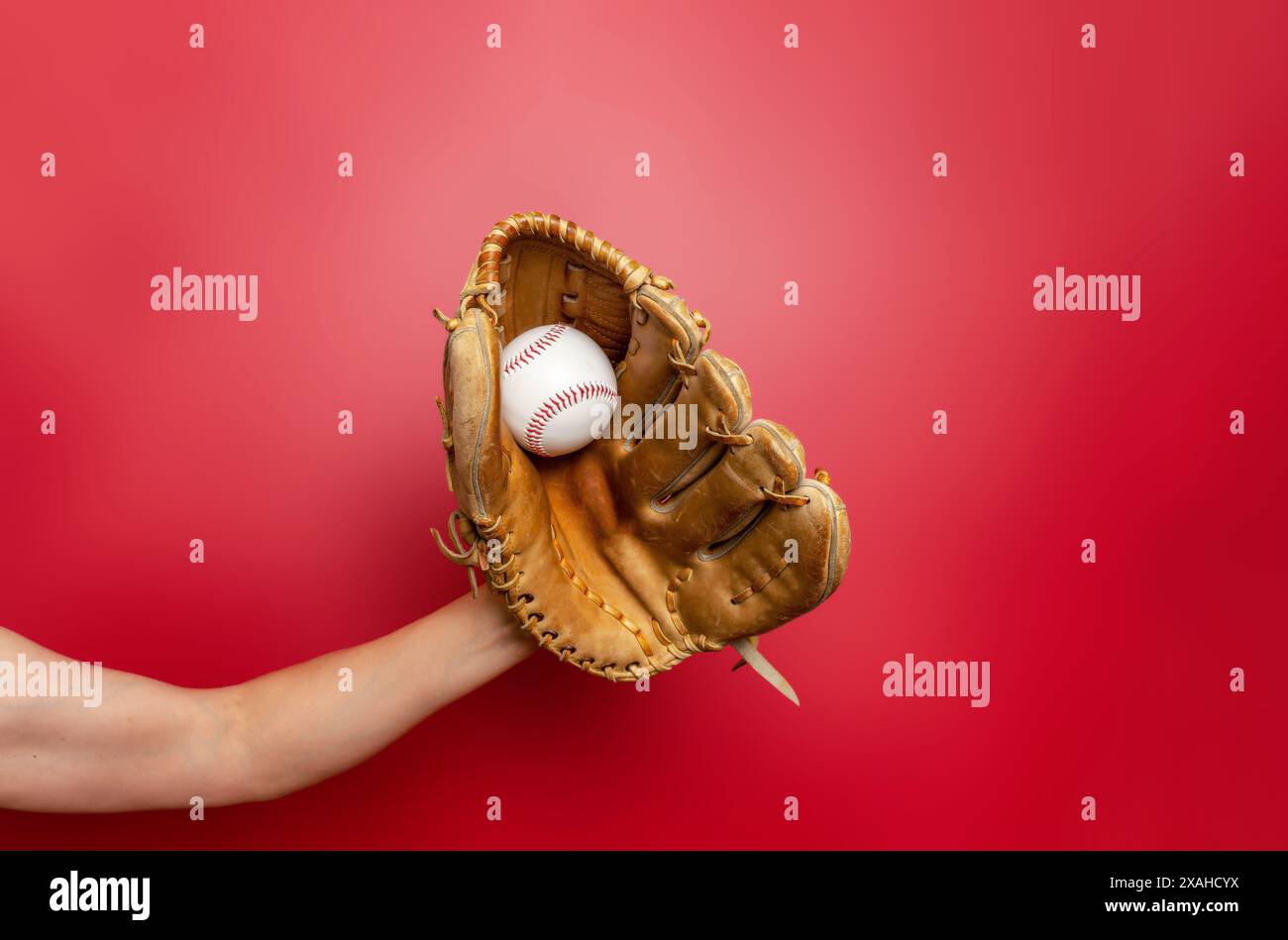Female baseball gloved hand catches ball. Red background. Active sport ...