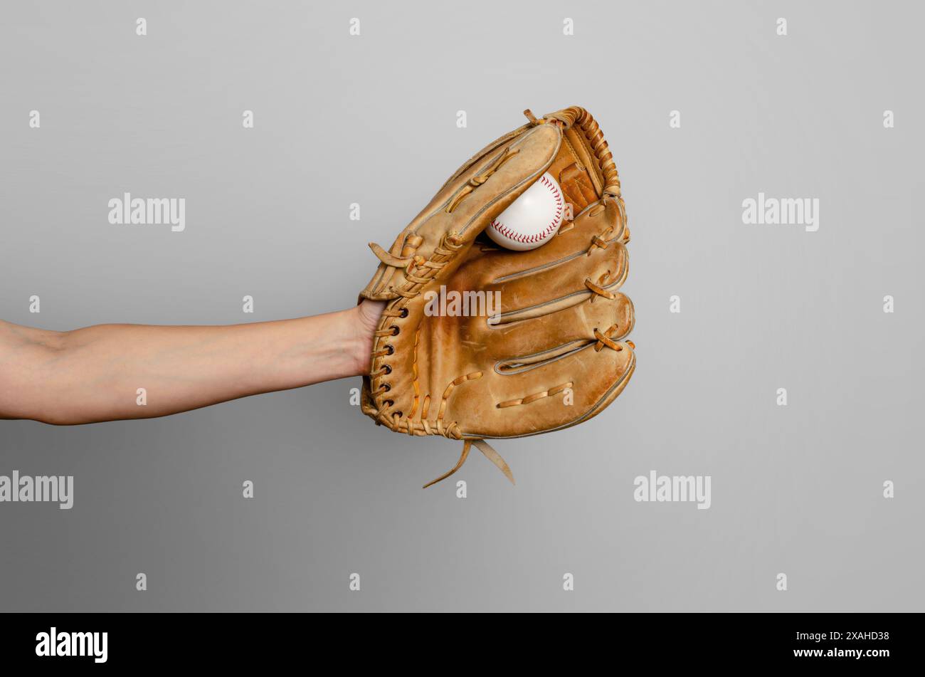 Female baseball gloved hand catches ball. Gray background. Active sport ...