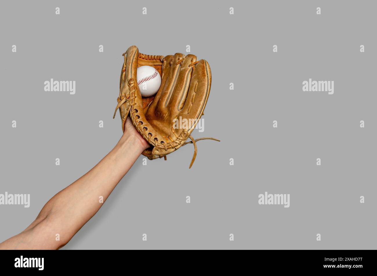 Female baseball gloved hand catches ball. Gray background. Active sport ...