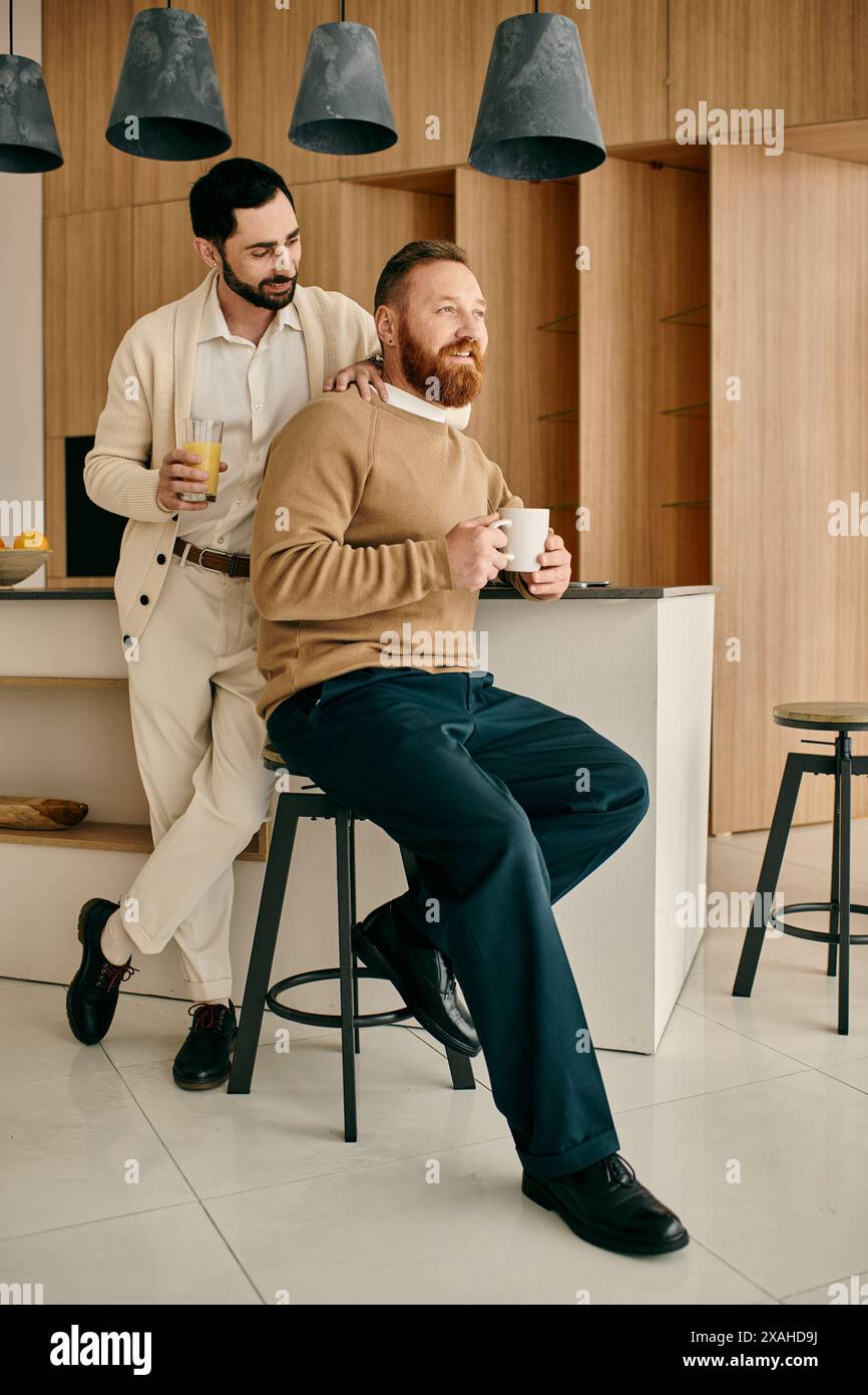 Two men enjoying a moment on stools in a kitchen of a modern apartment ...