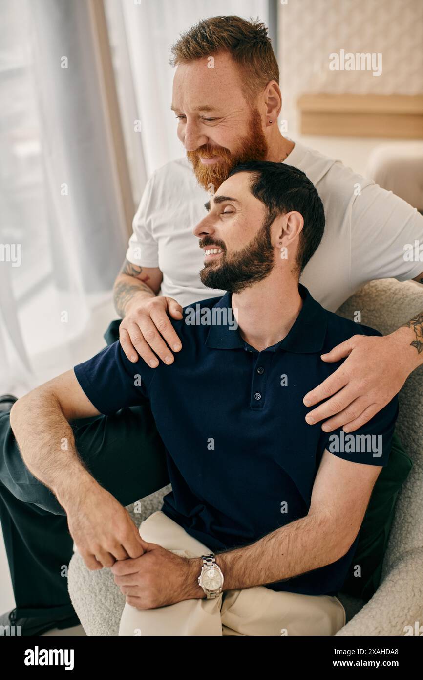 Two men in casual clothes hugging warmly on a cozy couch in a modern ...