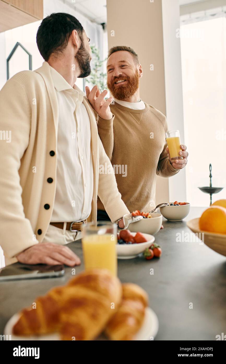 Two happy gay men enjoy breakfast together in a modern kitchen, sharing ...