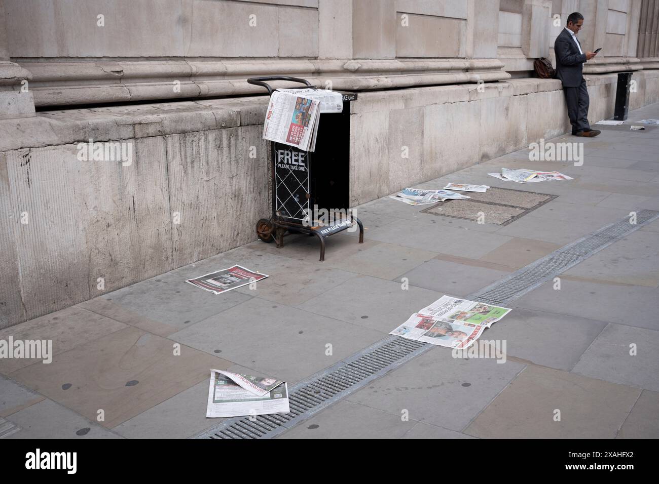 Old copies of newspapers remain blowing in the breeze on the pavement ...