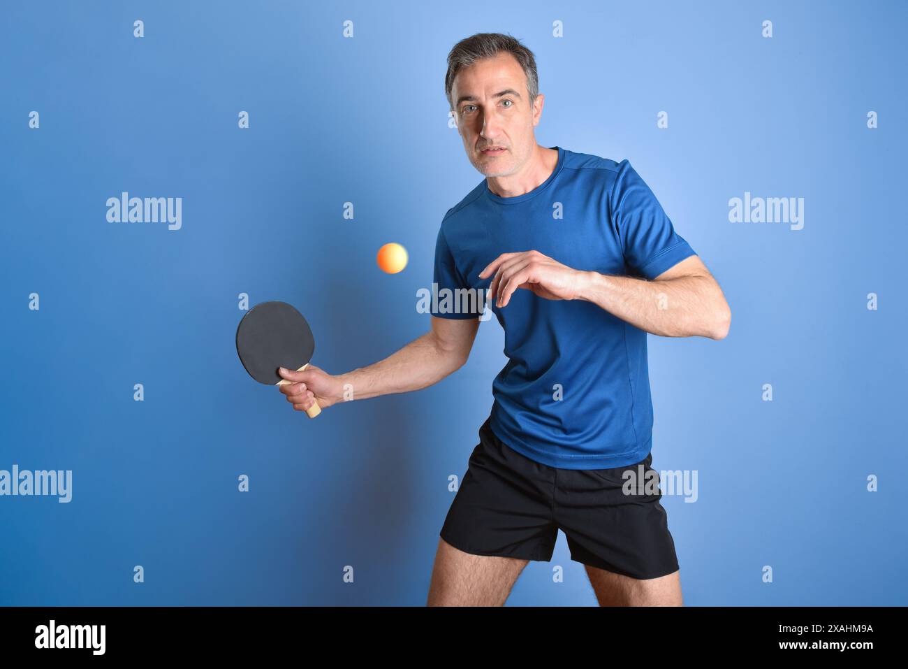 Portrait of concentrated ping pong player going to hit an orange ball ...