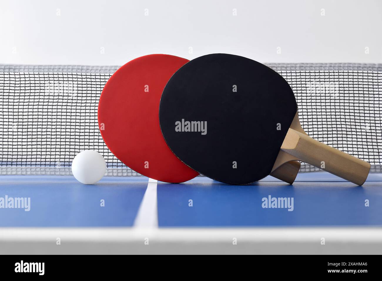 View of ping pong set with paddles resting on the net and blue game ...