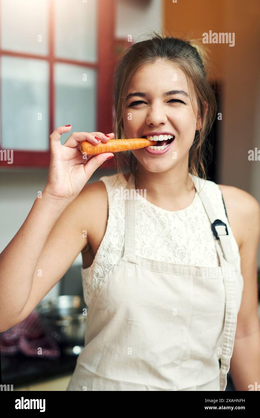 Food, face or girl eating carrot in kitchen for wellness, health or ...
