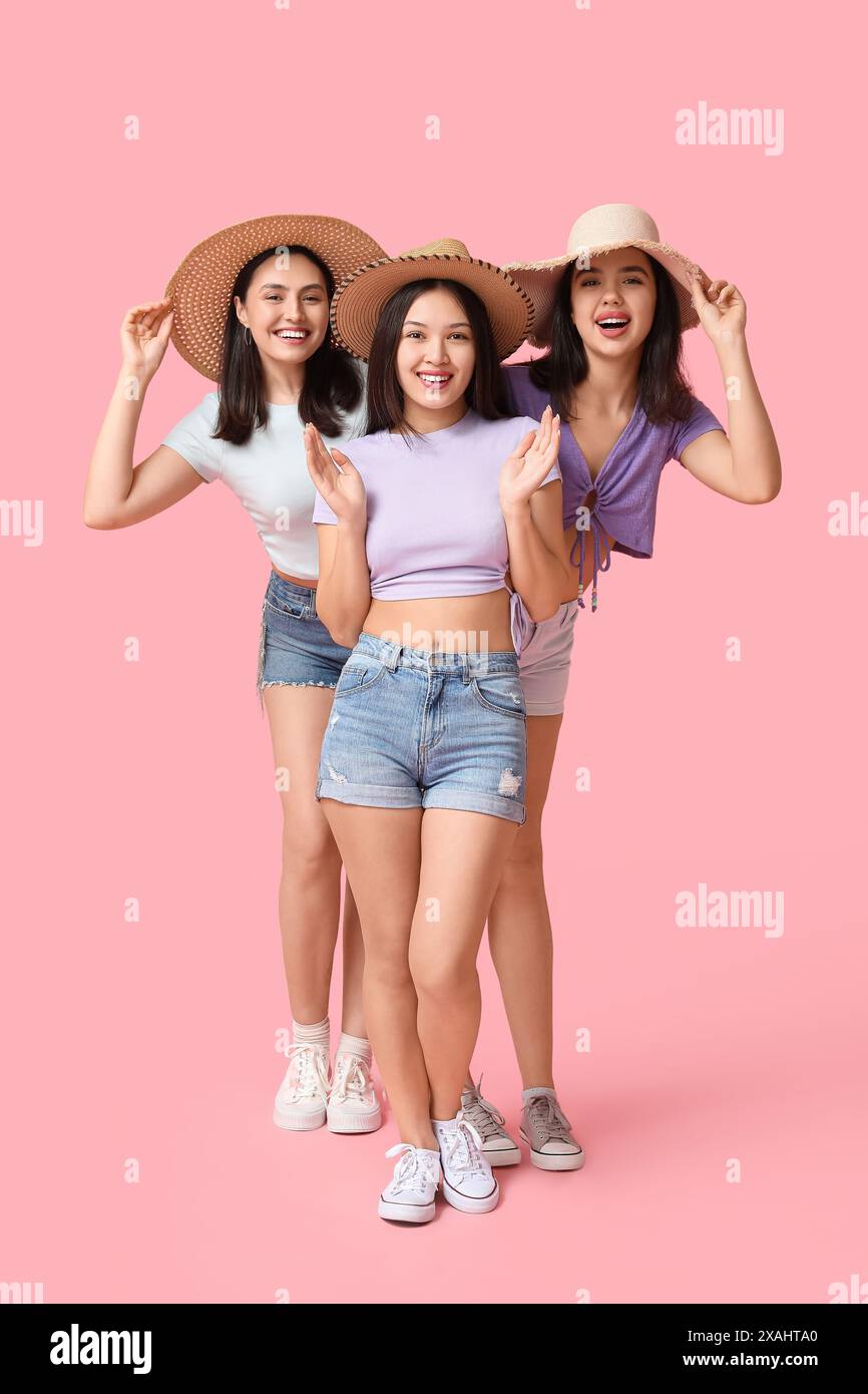 Beautiful young women in wicker hats on pink background. Summer party ...