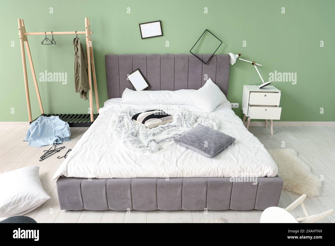 Interior of messy bedroom with frames and clothes rack Stock Photo - Alamy