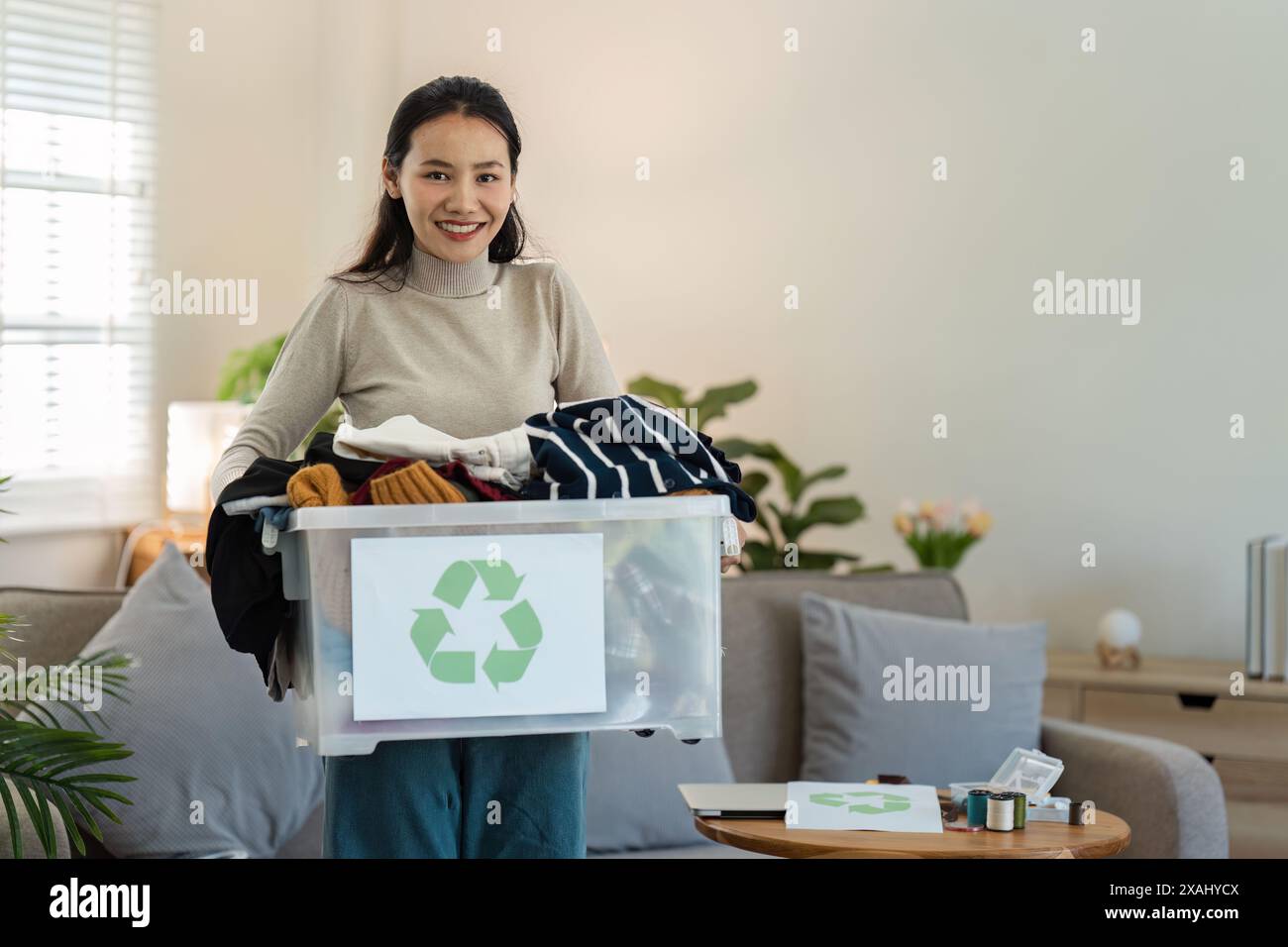 Young Woman Holding a Recycling Bin Filled with Clothes in a Modern ...