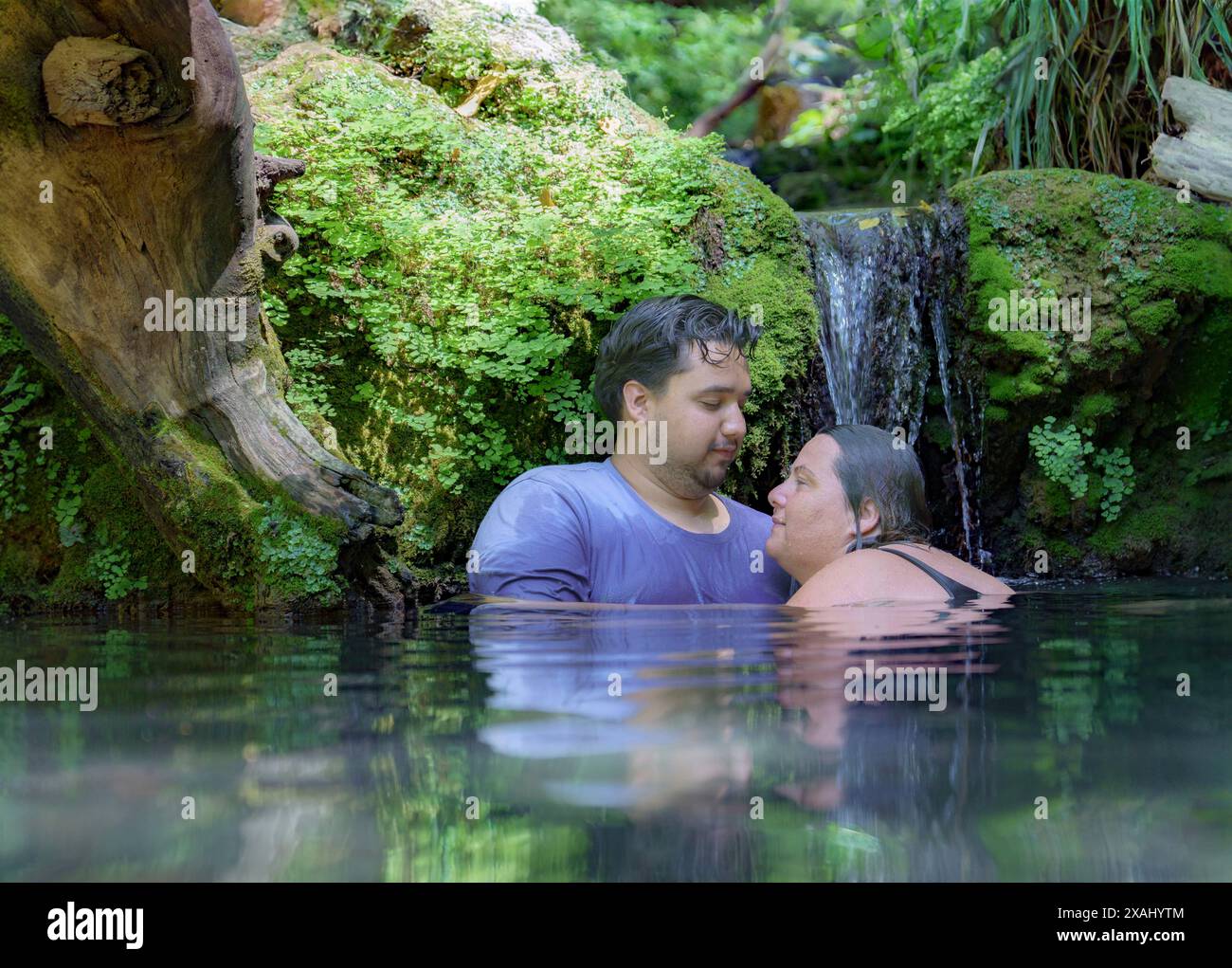 Mother and son embrace looking at each other while bathing in a river ...