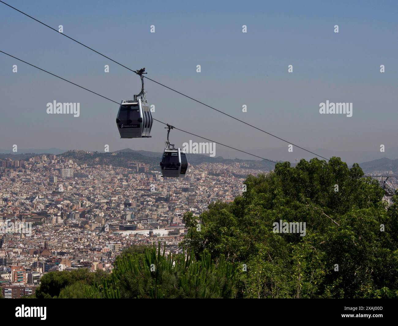 Two cable car carriages hovering over an expansive city view, Barcelona ...