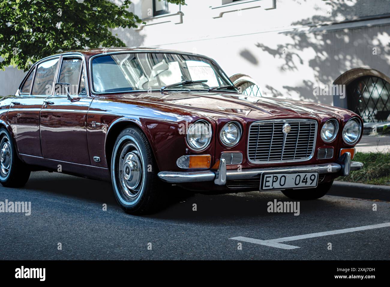 Red old car Jaguar on road in town between buildings Stock Photo - Alamy