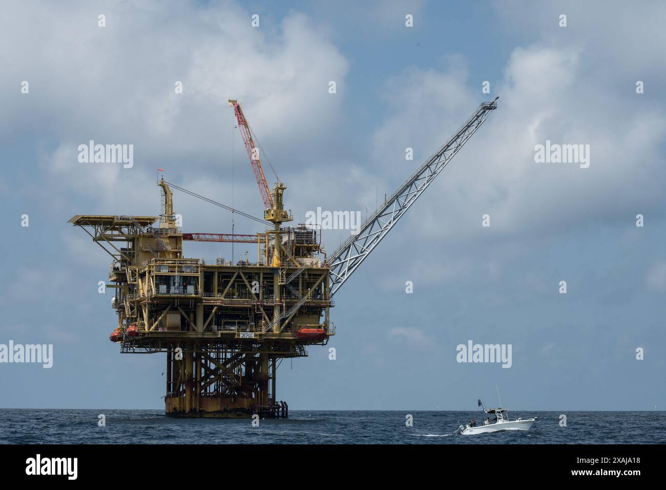 Anglers aboard a fishing boat target tuna near a large floating oil ...