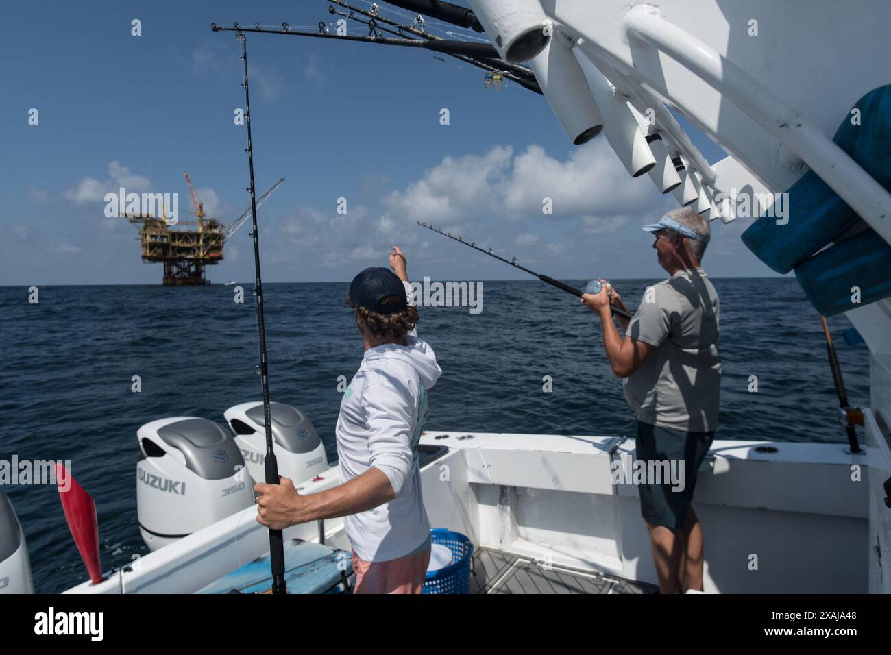 An angler reels in a tuna caught near floating oil rigs in the Gulf of ...