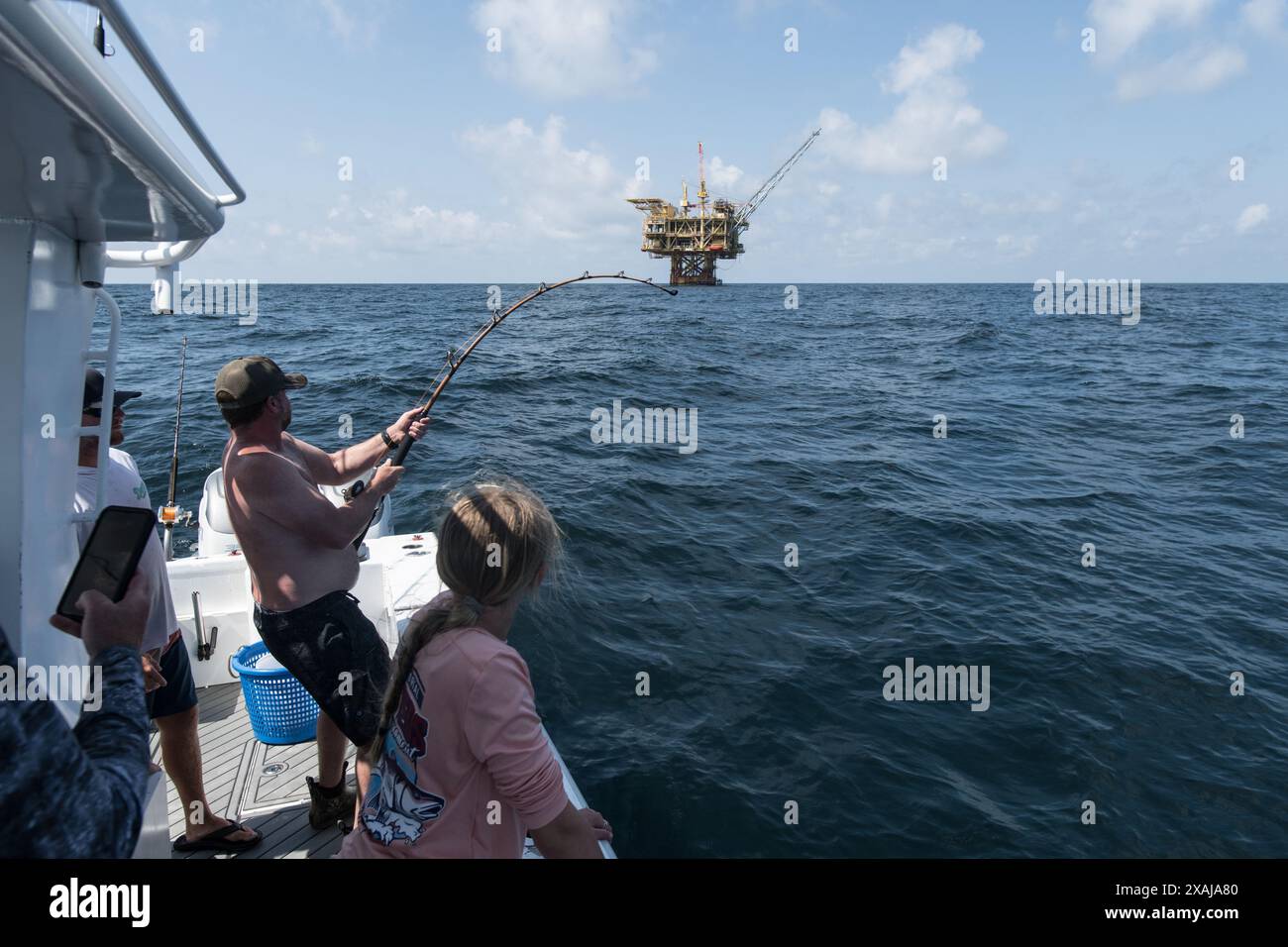 An angler reels in a tuna caught near floating oil rigs in the Gulf of ...