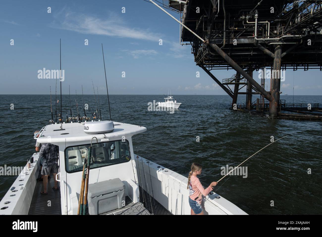 Anglers aboard a fishing boat near offshore oil rigs in the Gulf of ...