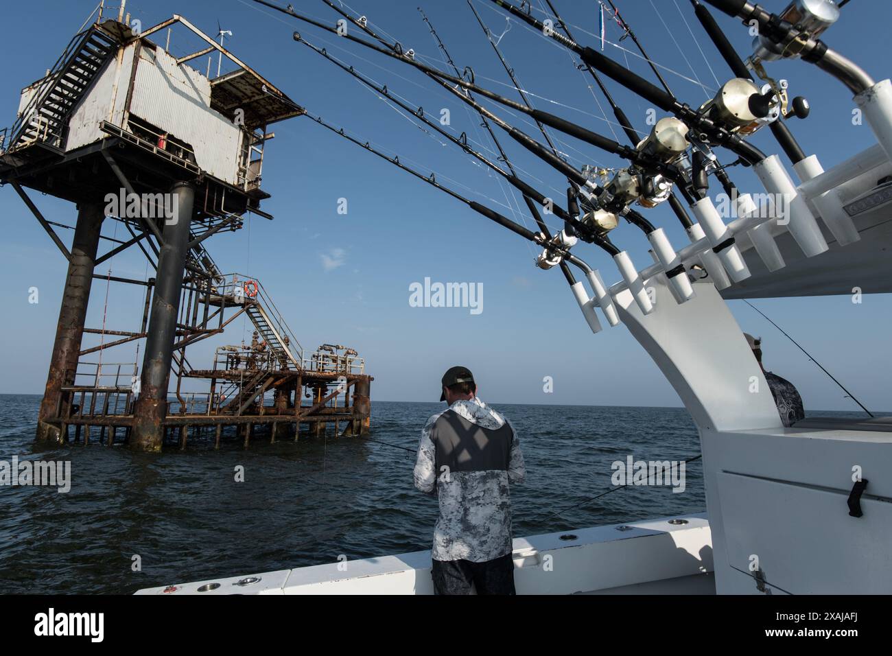An angler fishes for baitfish while surrounded by offshore oil ...