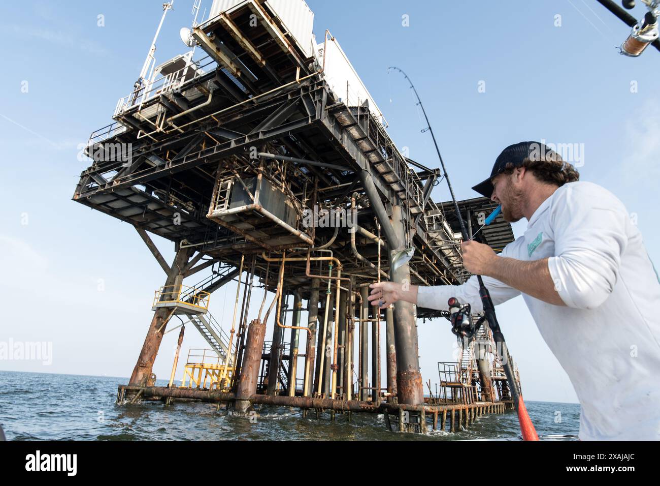 An angler fishes for baitfish while surrounded by offshore oil ...