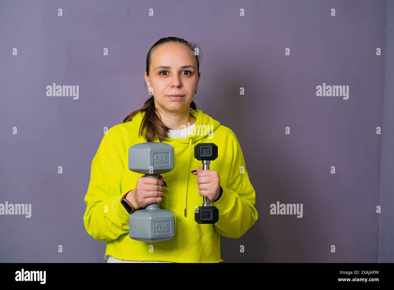 Woman Holding Two Dumbbells During Workout in Gym. The image showcases ...