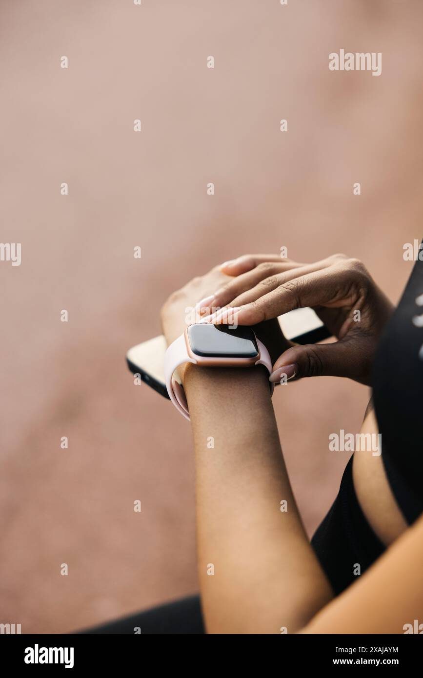 Close-up of a woman adjusting her smartwatch, focusing on her wrist and ...
