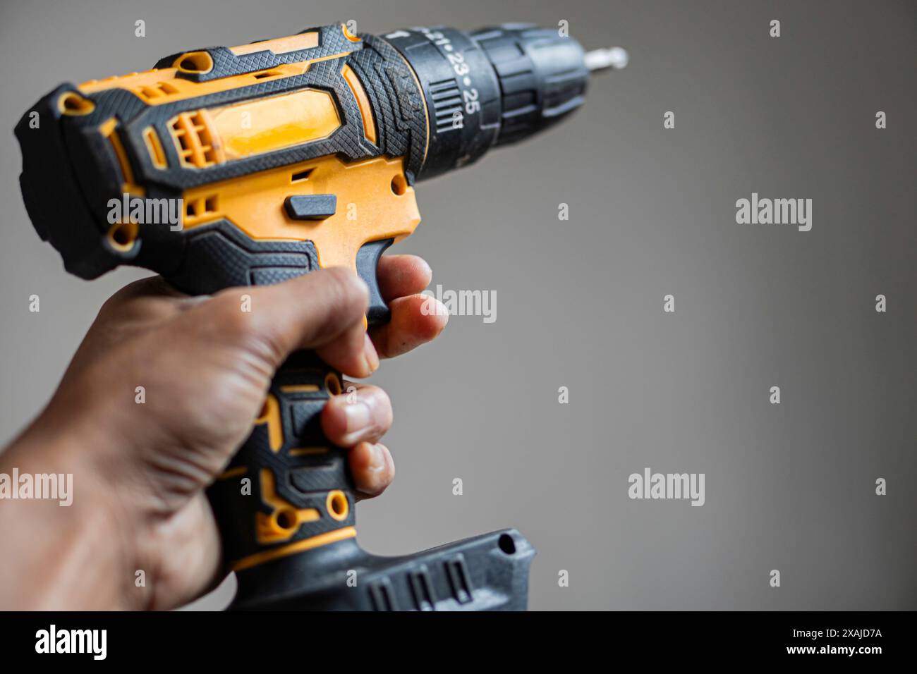 Close-up of a hand holding a cordless power drill with a yellow and ...
