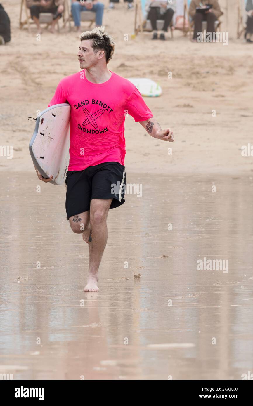 A surfer carrying his surfboard running to the sea to compete in the ...