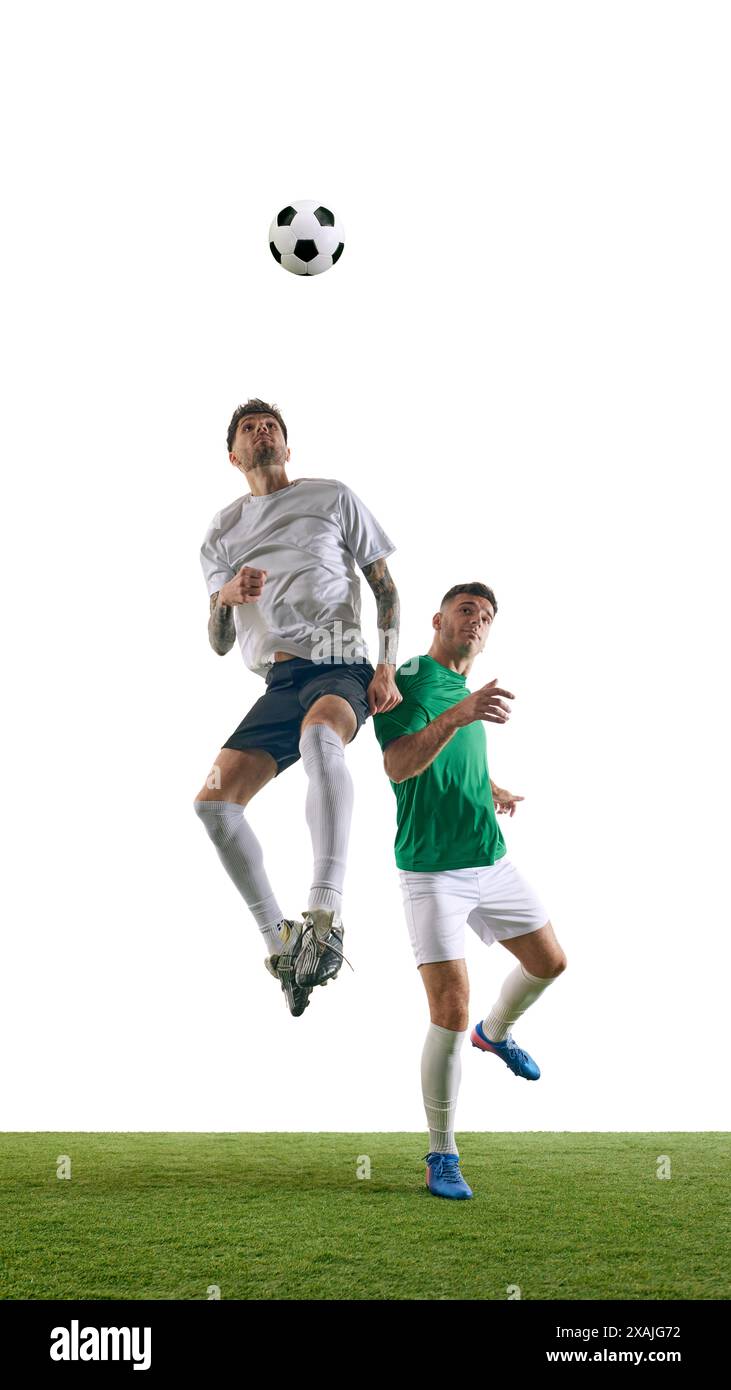 Two athletic men, soccer players in mid-air compete for ball on green ...