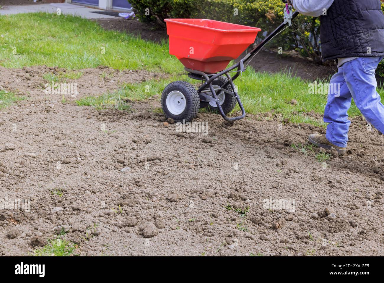 Drop lawn spreader used for sowing lawn grass seeds in residential back ...
