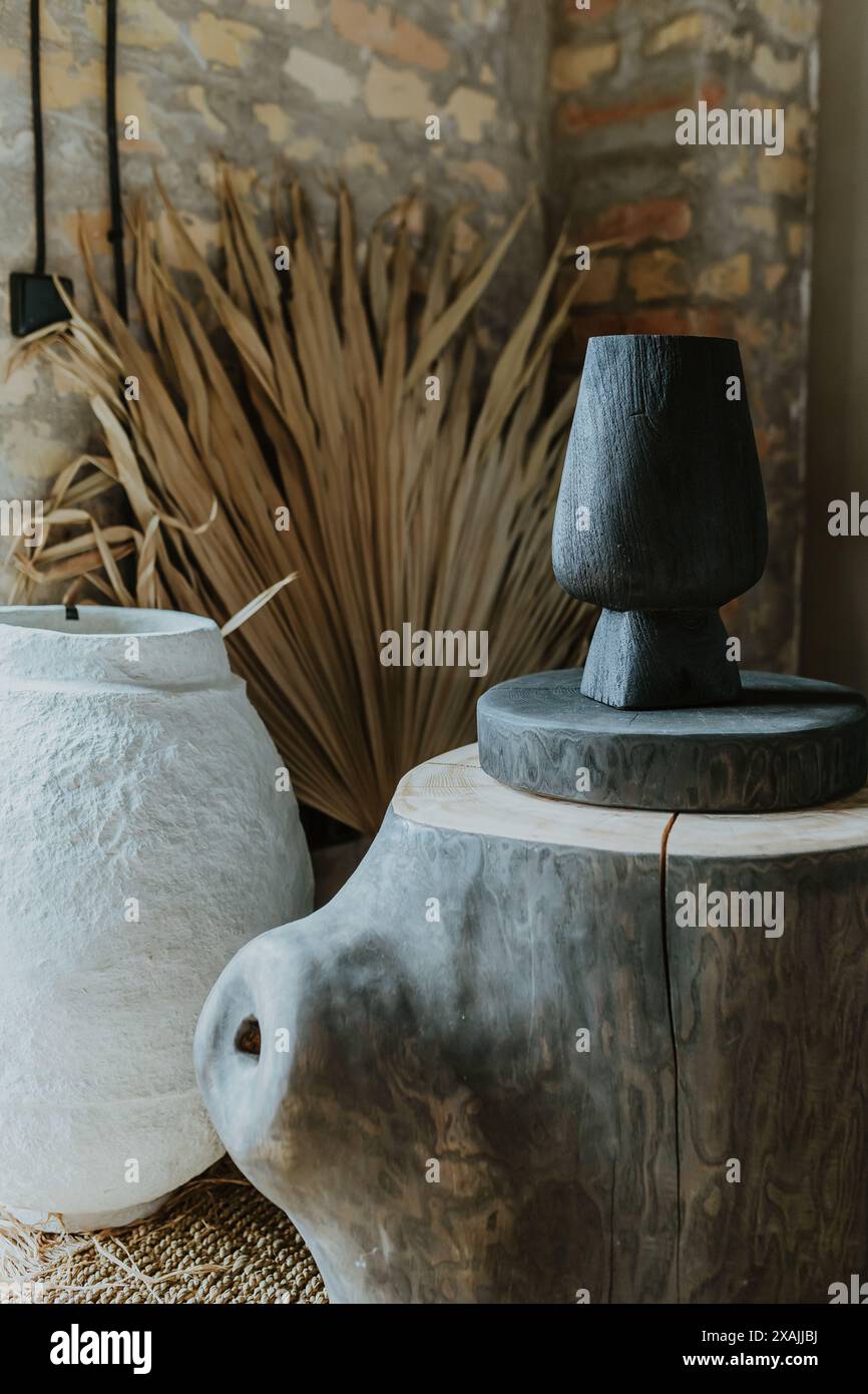 Cosy corner with a black wooden textured vase on a wooden side table ...