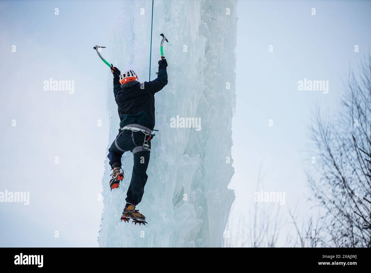 Ice climber ascending a frozen ice tower in Kitzbühel, Tyrolean Alps ...