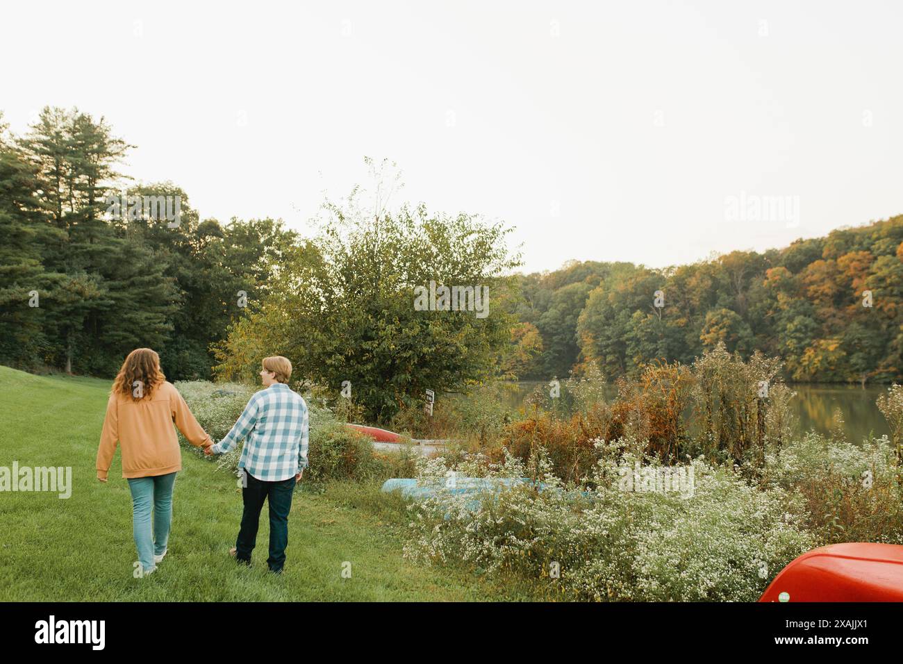 Peaceful couple walks by serene lake in fall and canoes Stock Photo - Alamy