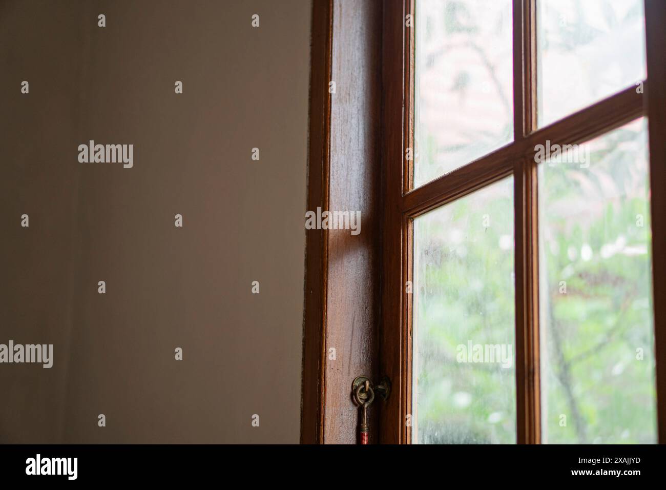 A close-up view of a wooden-framed window with glass panes. The window ...