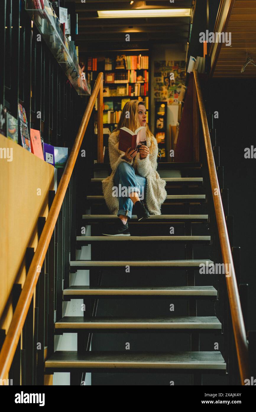 Woman reading book in bookstore Stock Photo - Alamy