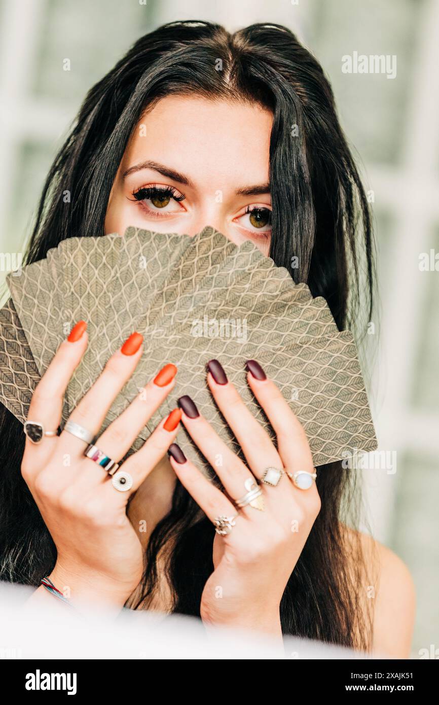 Caucasian girl peeking over cards with colored fingernails Stock Photo ...