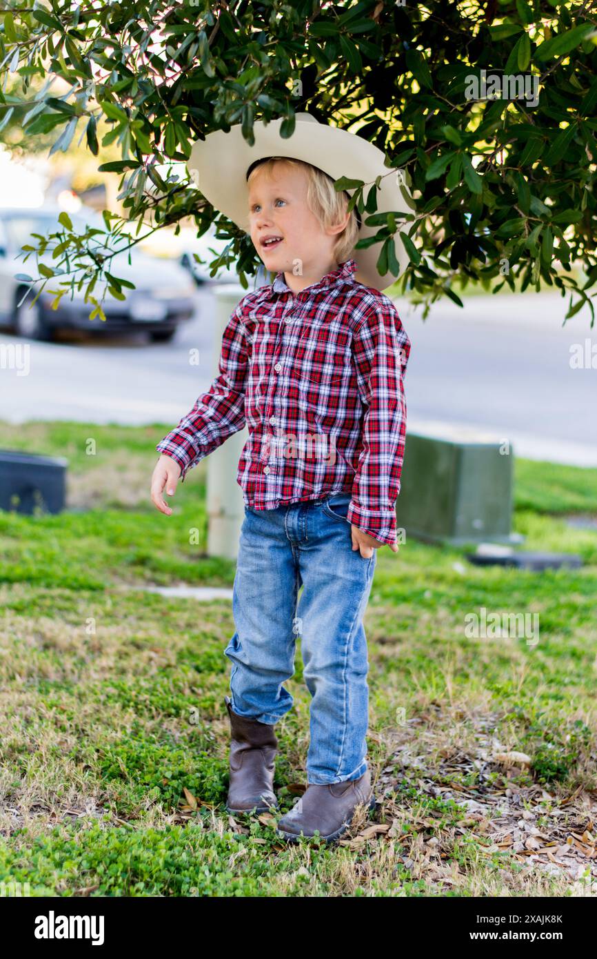 Young cowboy in western attire standing by a tree Stock Photo - Alamy