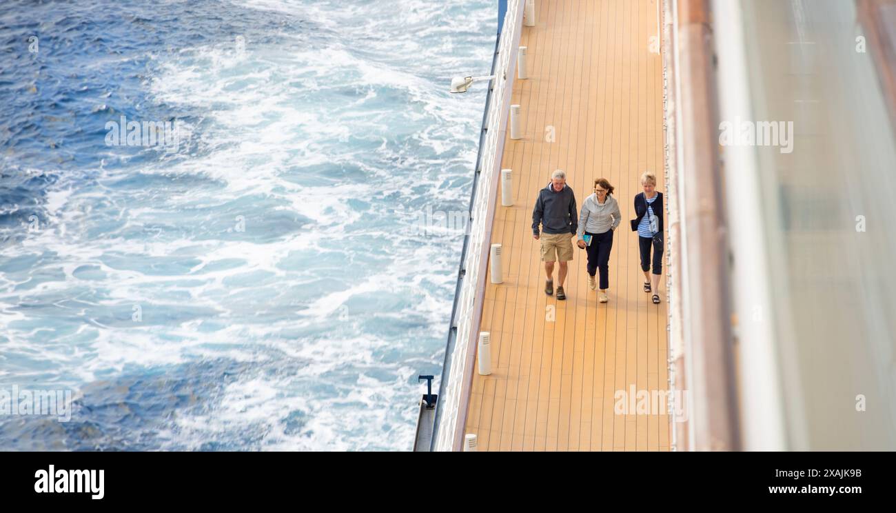 Senior, mature cruise ship passengers taking a brisk walk in the clean ...