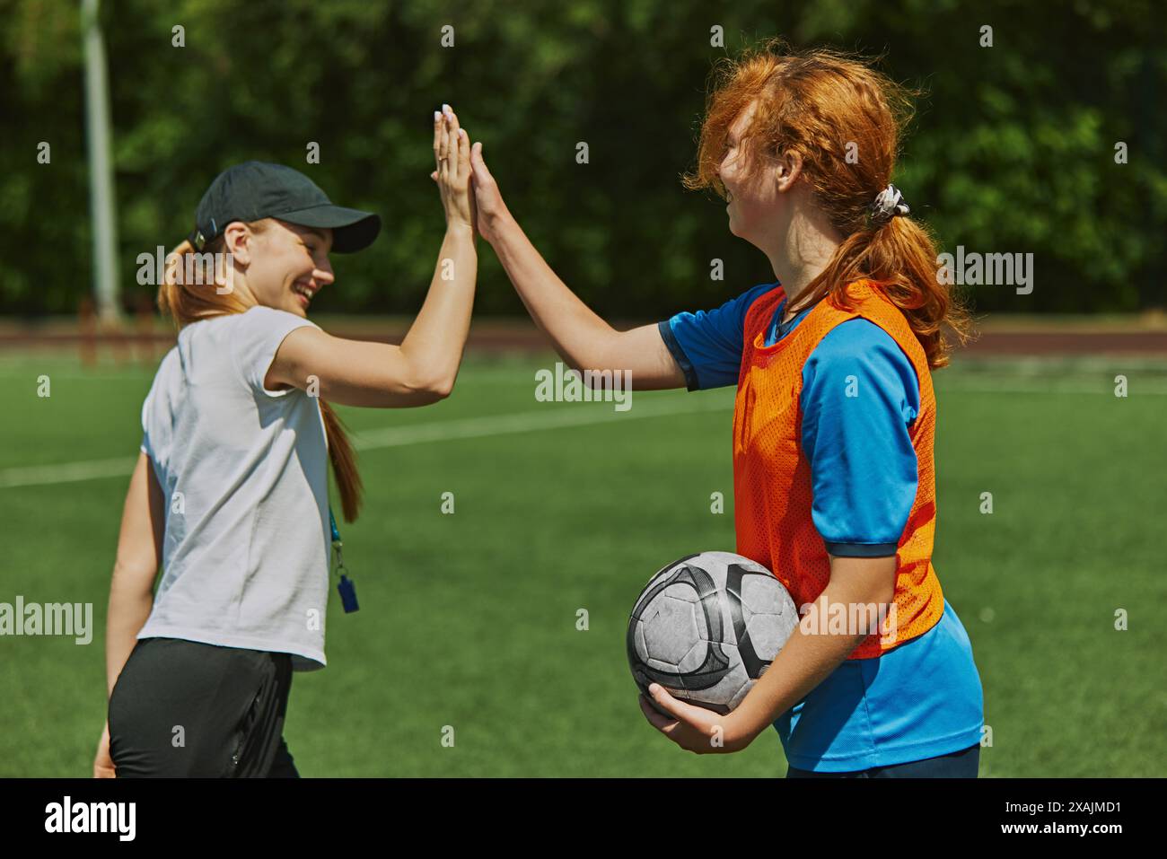 Female soccer coach giving high five to girl, football player after ...