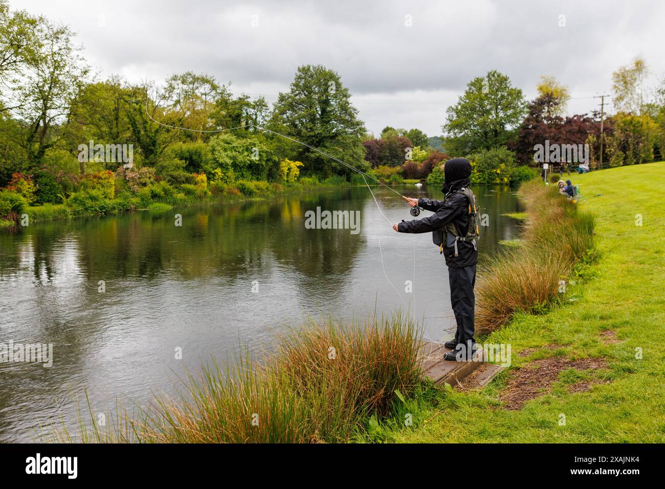 A portrait of a teenage boy in full fishing clothes with his rod over ...