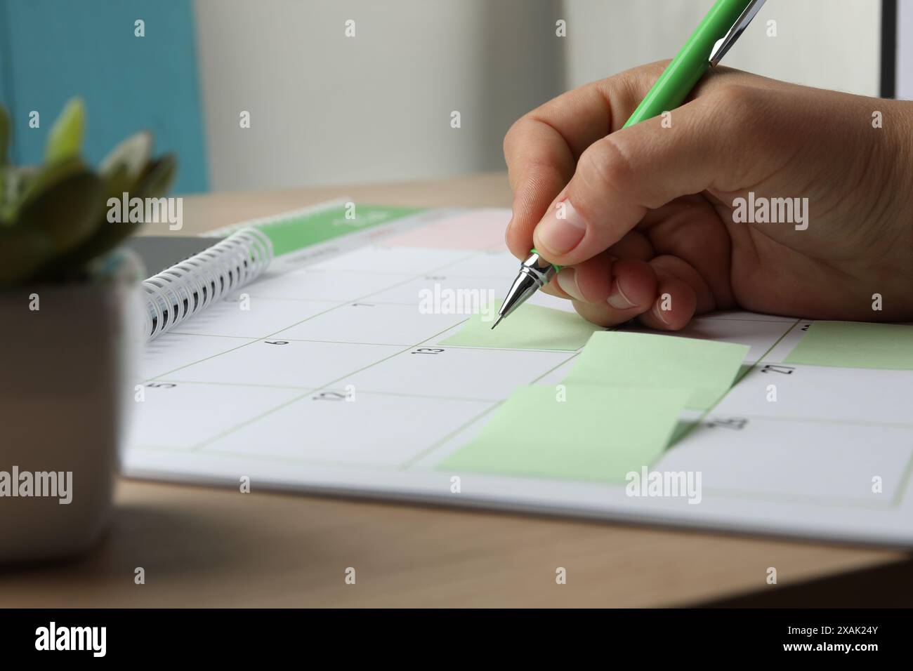 Timetable. Man making schedule using calendar and sticky note at table ...