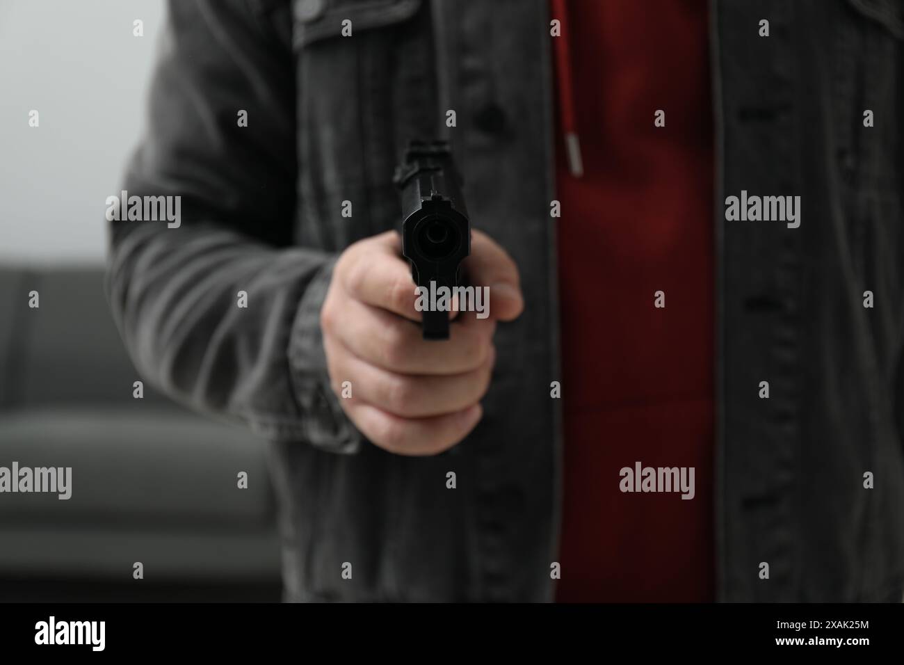 Dangerous criminal with gun indoors, closeup. Armed robbery Stock Photo ...