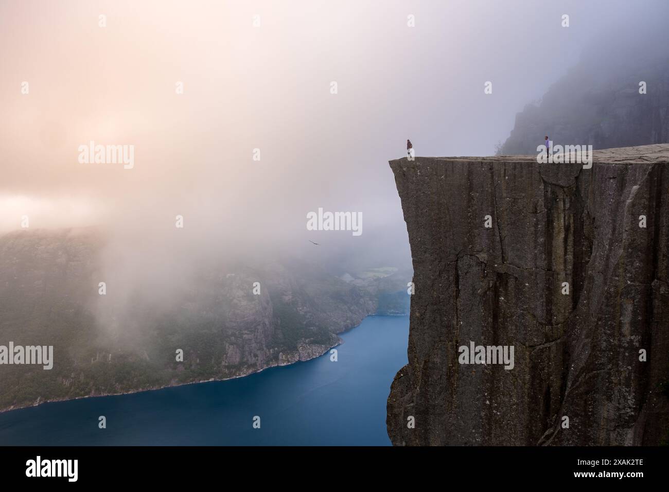 A misty morning scene in Norway. Two figures stand on the edge of ...