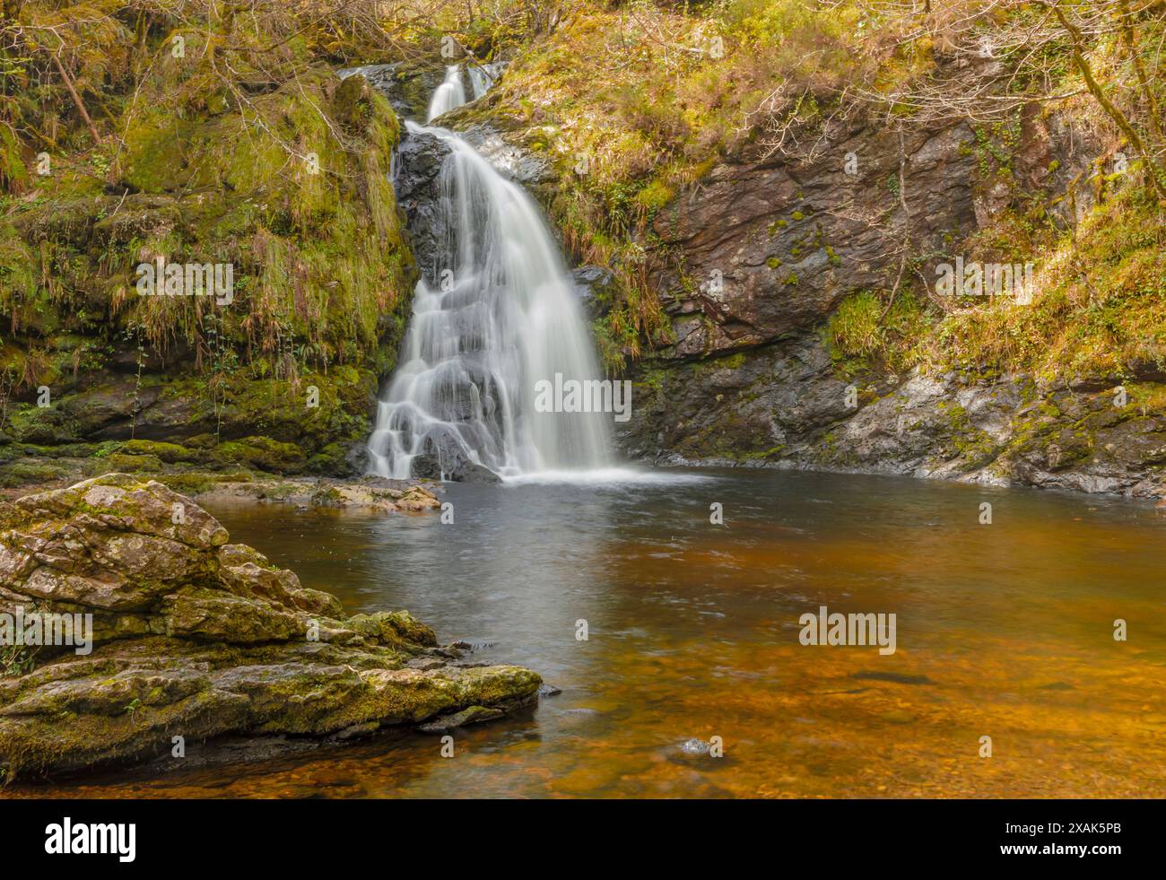 Clear orange coloured waters of an irish waterfall tumbling down a ...