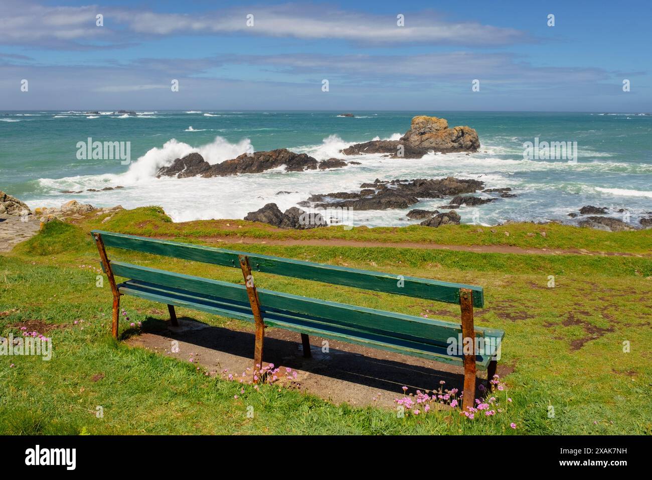 Bench on coast path with rough seas in Portelet bay, Torteval, Guernsey ...