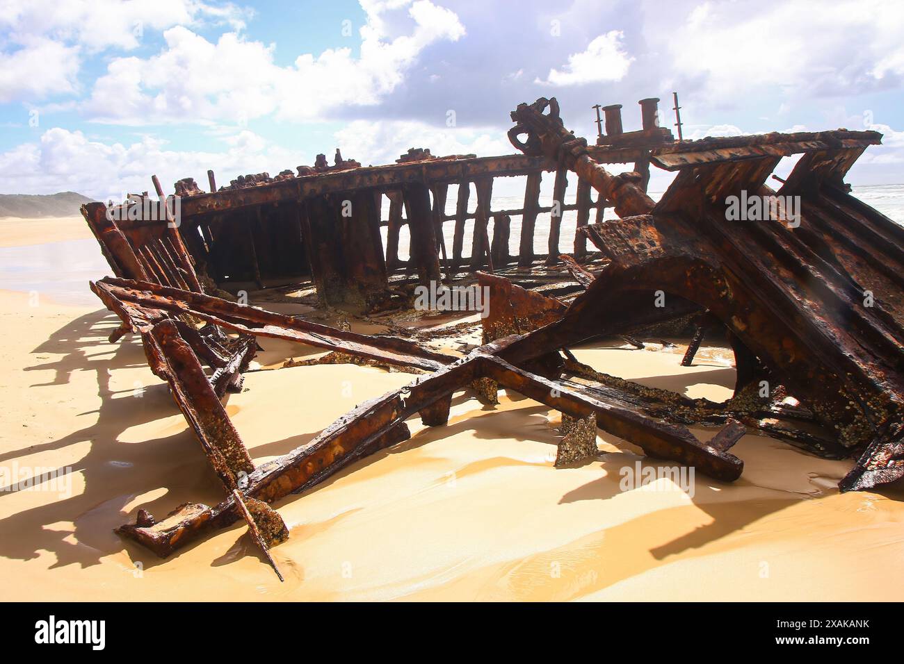 Rusty crumbling piece of the SS Maheno shipwreck half buried in the ...
