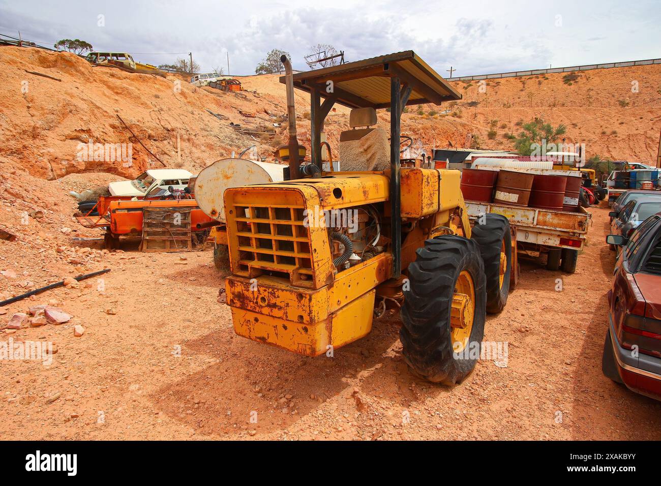 Old tractor in a unkyard of rusty abandoned vintage cars in the desert ...